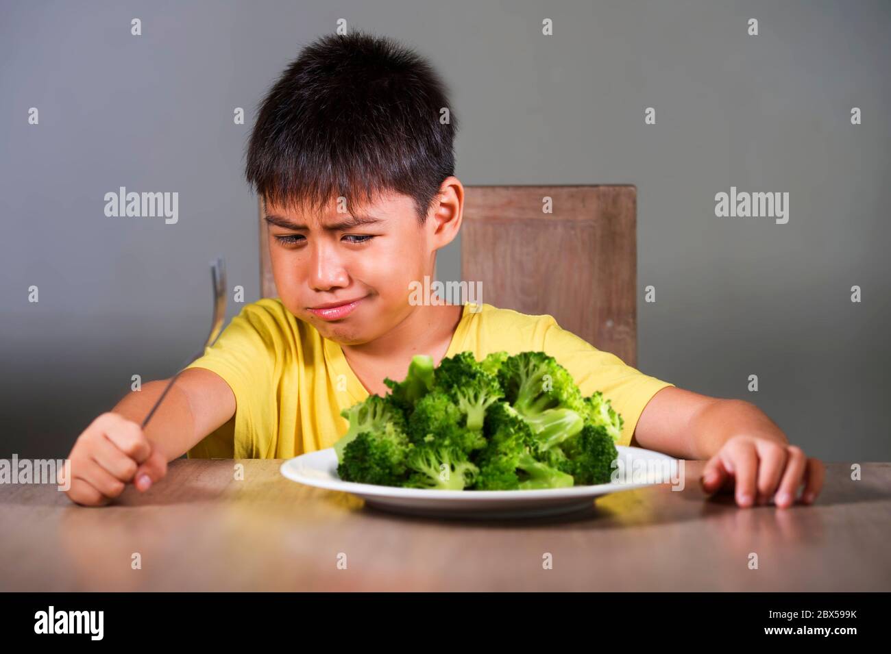 7 or 8 years old upset and disgusted Asian kid sitting on table in ...
