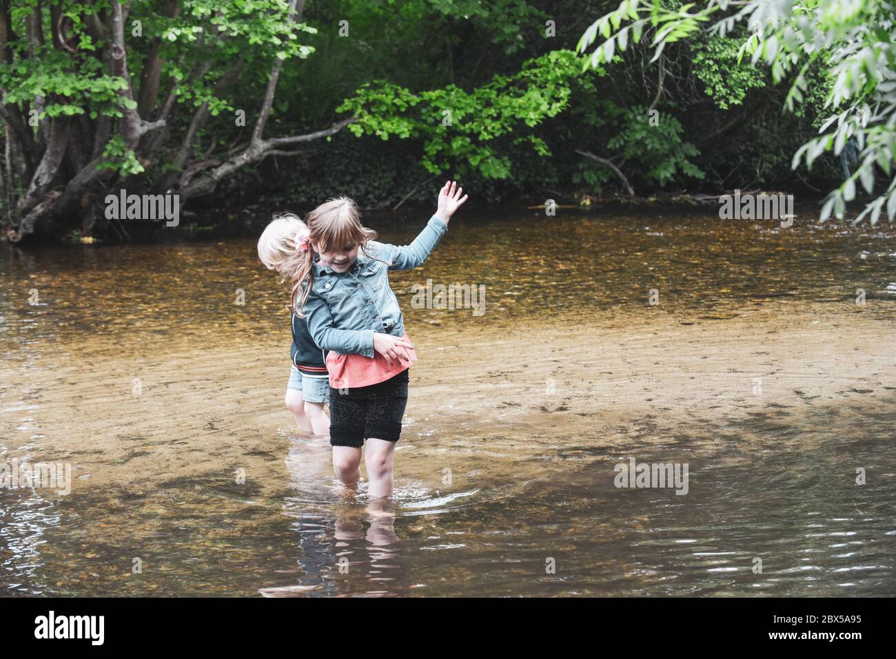 Children playing outside in a shallow stream paddling in the water ...