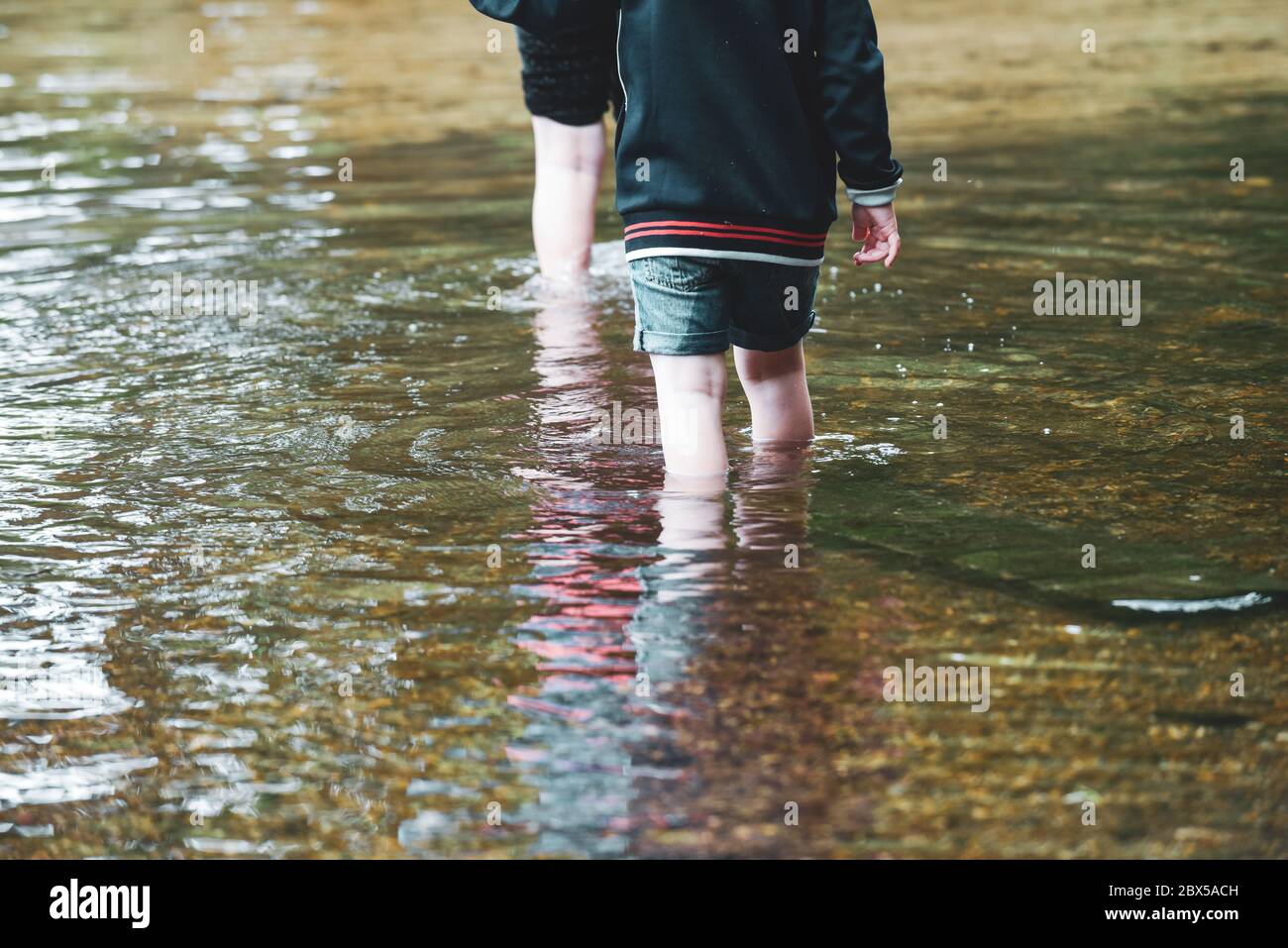 Children playing outside in a shallow stream paddling in the water ...