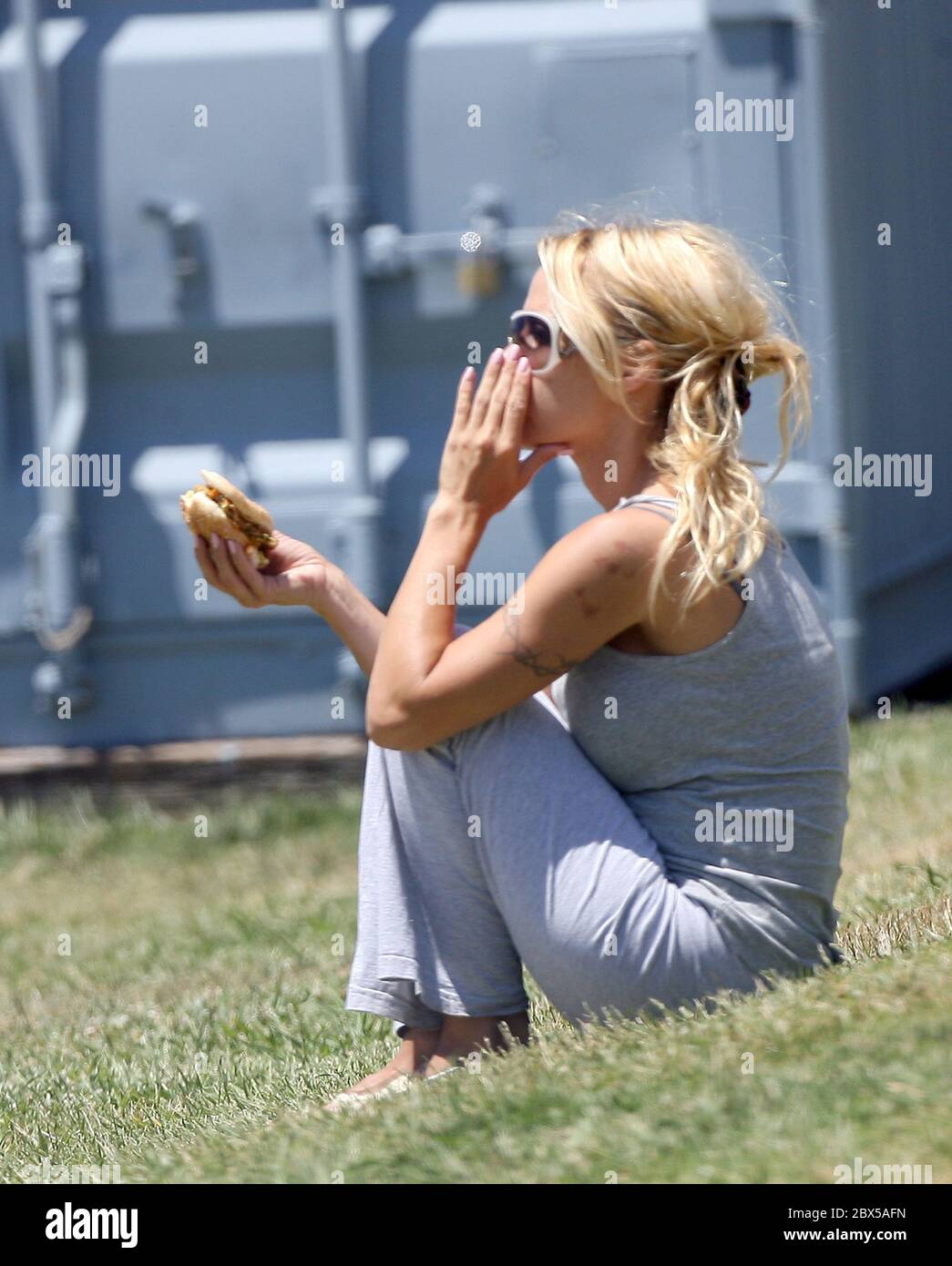 Pamela Anderson sitting on grass, eating burger in Malibu, CA May 2008 ...