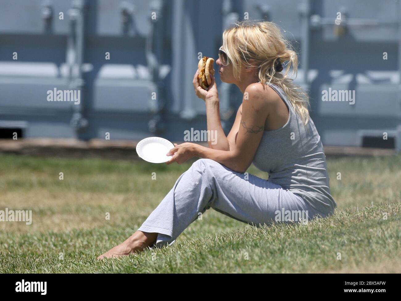 Pamela Anderson sitting on grass, eating burger in Malibu, CA May 2008 ...