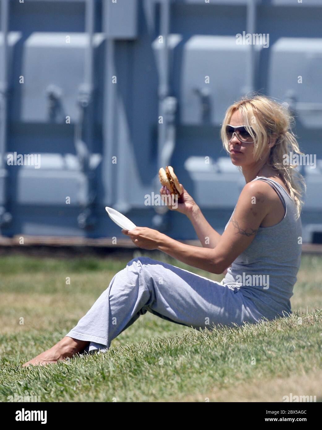 Pamela Anderson sitting on grass, eating burger in Malibu, CA May 2008 ...