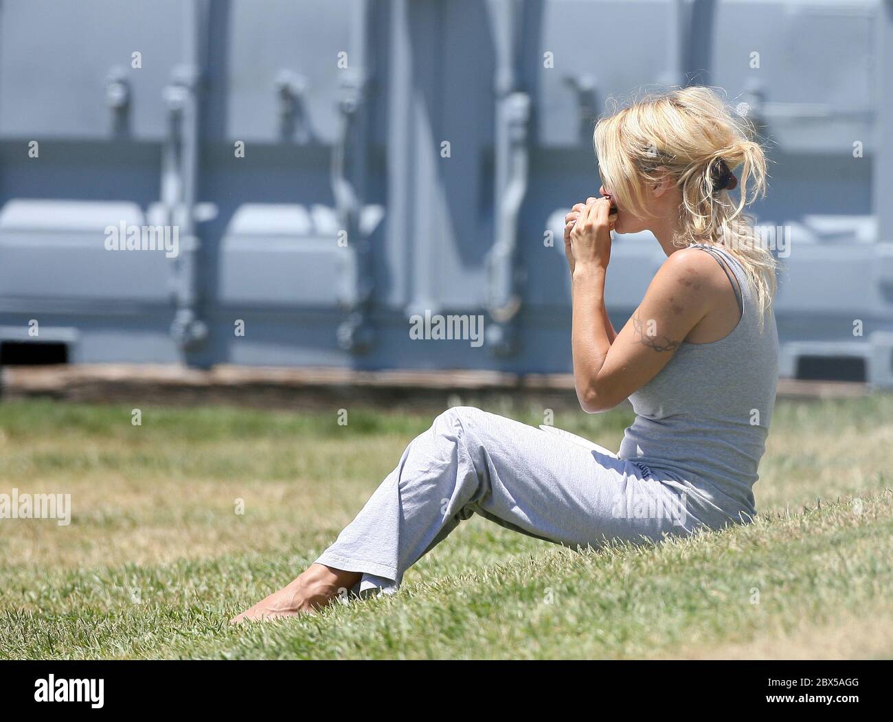 Pamela Anderson sitting on grass, eating burger in Malibu, CA May 2008 ...