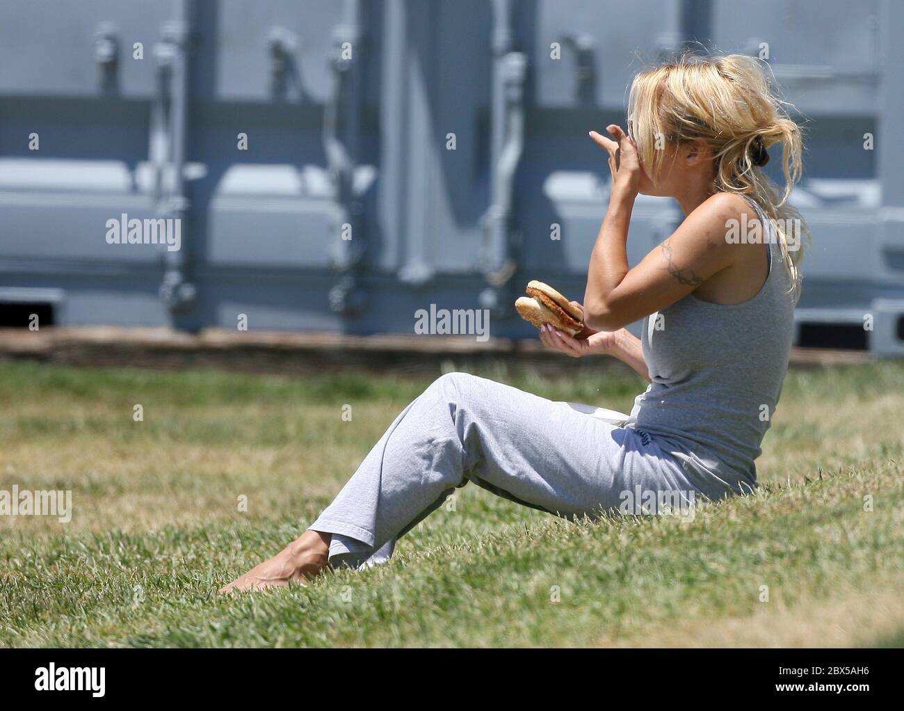 Pamela Anderson sitting on grass, eating burger in Malibu, CA May 2008 ...