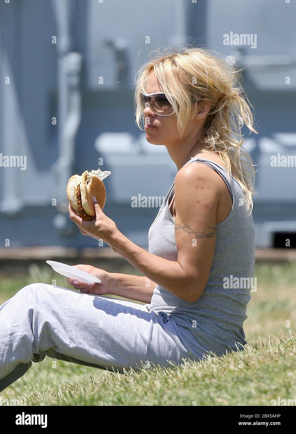 Pamela Anderson sitting on grass, eating burger in Malibu, CA May 2008 ...