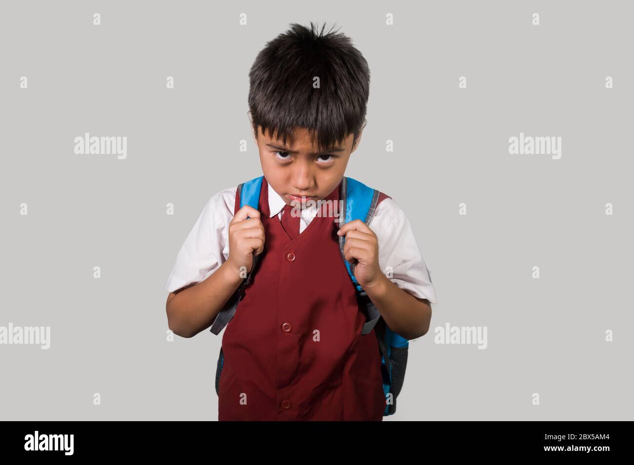 young child 7 or 8 years old in school uniform and schoolbag feeling ...