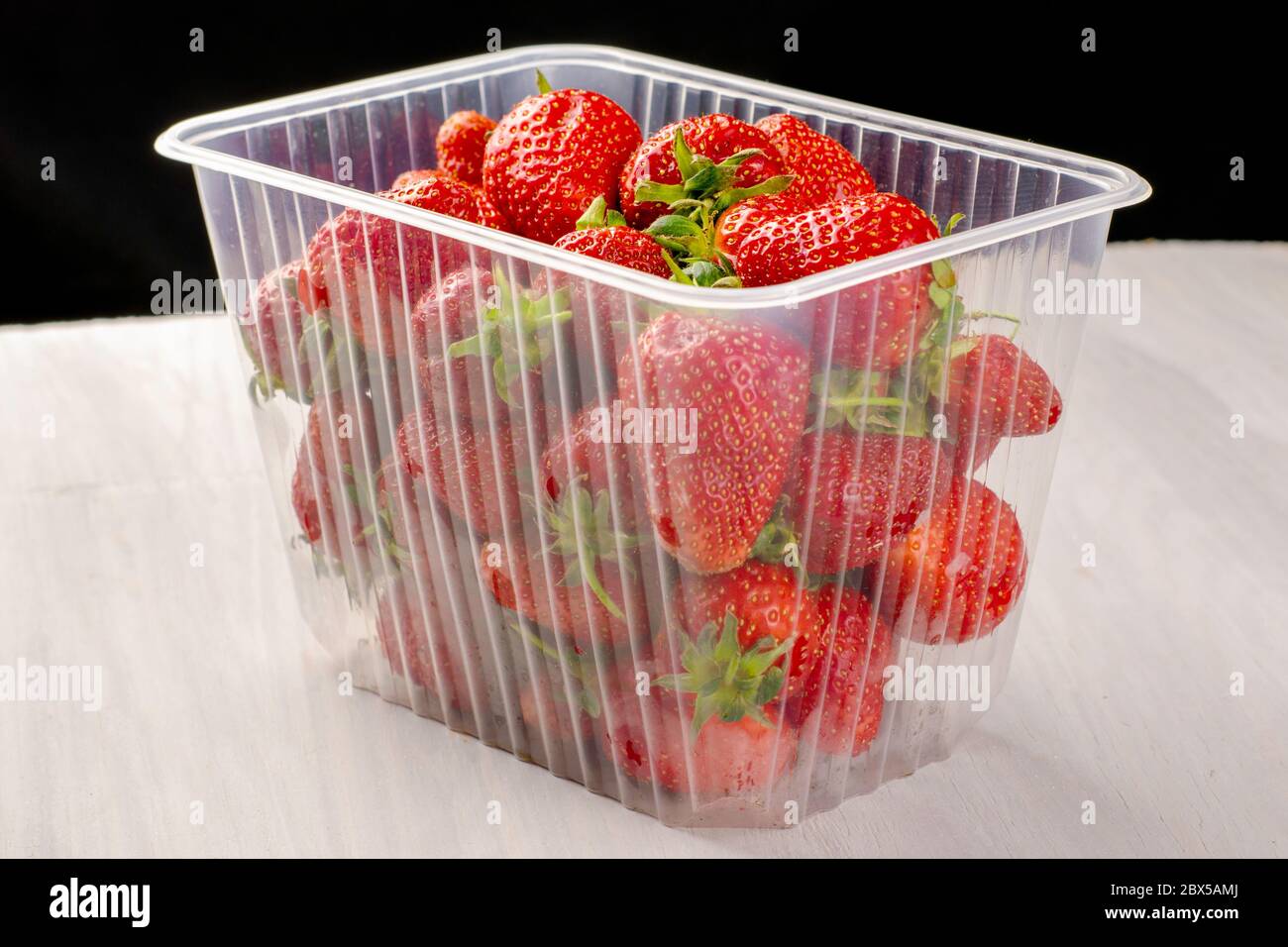 transparent plastic container with red ripe juicy strawberries is on ...