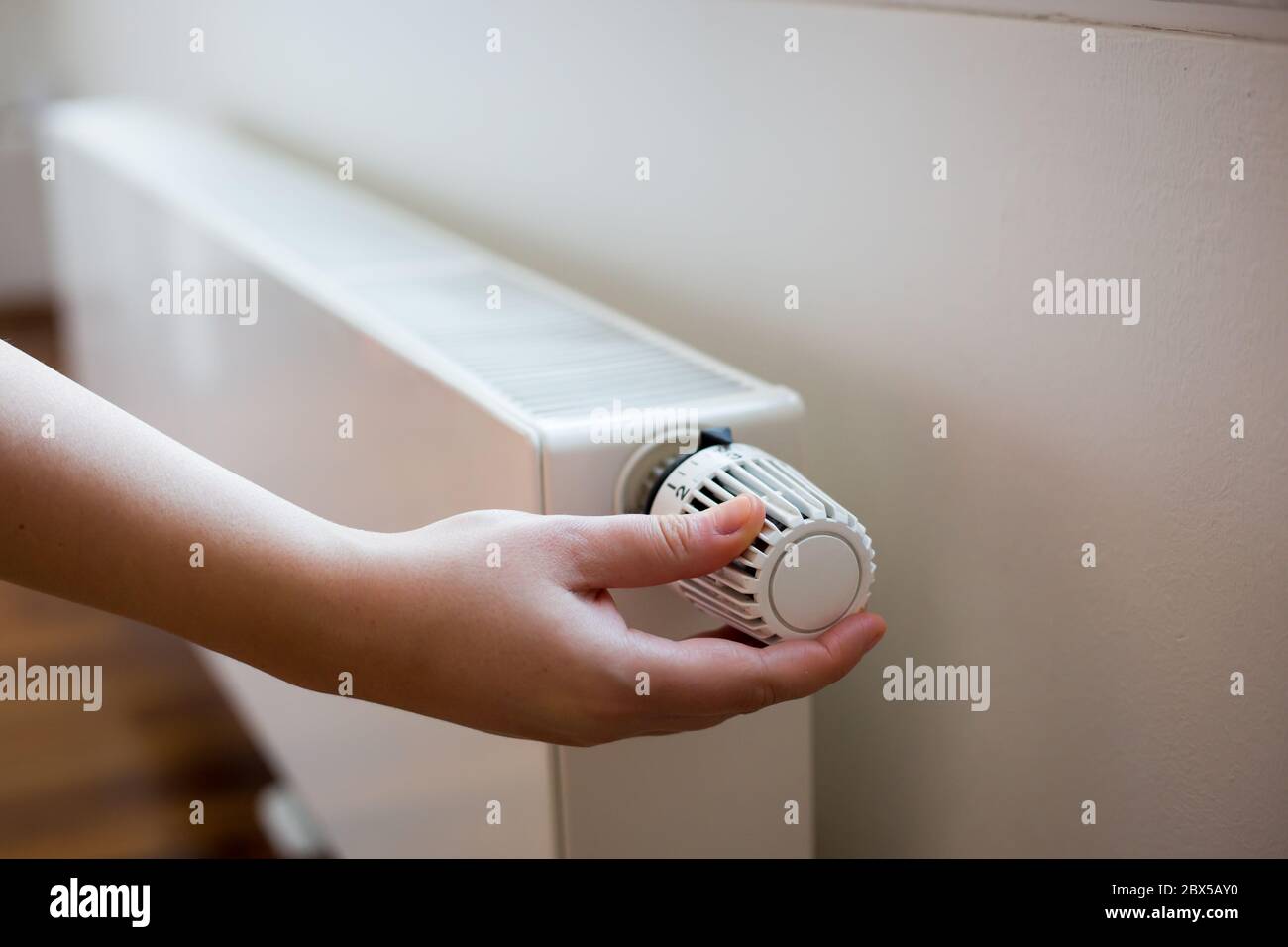 Woman changing the temperature on radiator by temperature controller ...