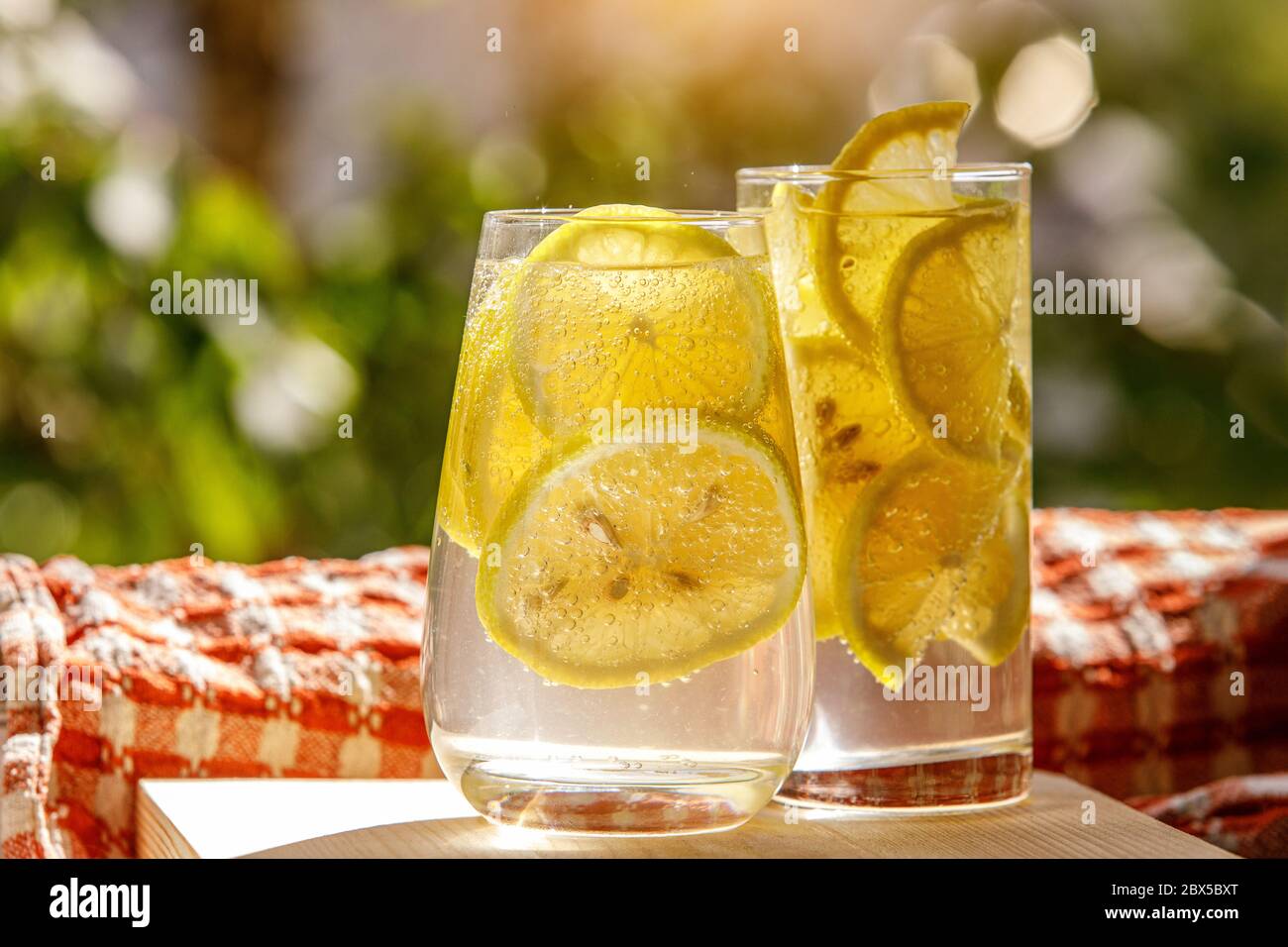 Lemonade with fresh lemon in glass on garden background Stock Photo - Alamy