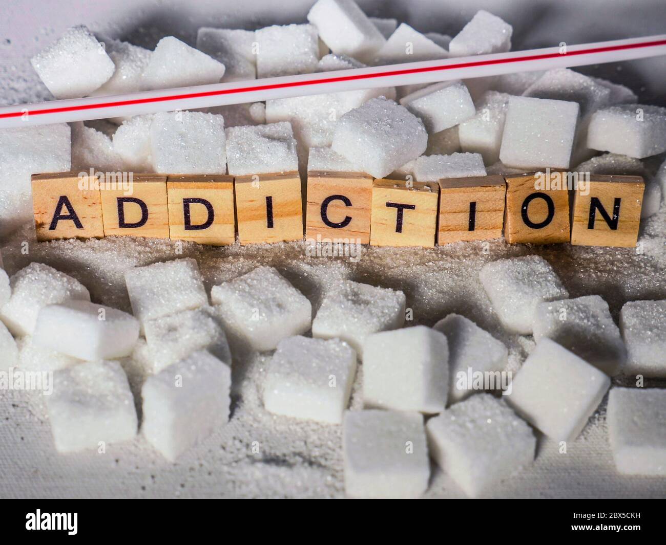 conceptual still life with pile of sugar cubes and addiction word in ...