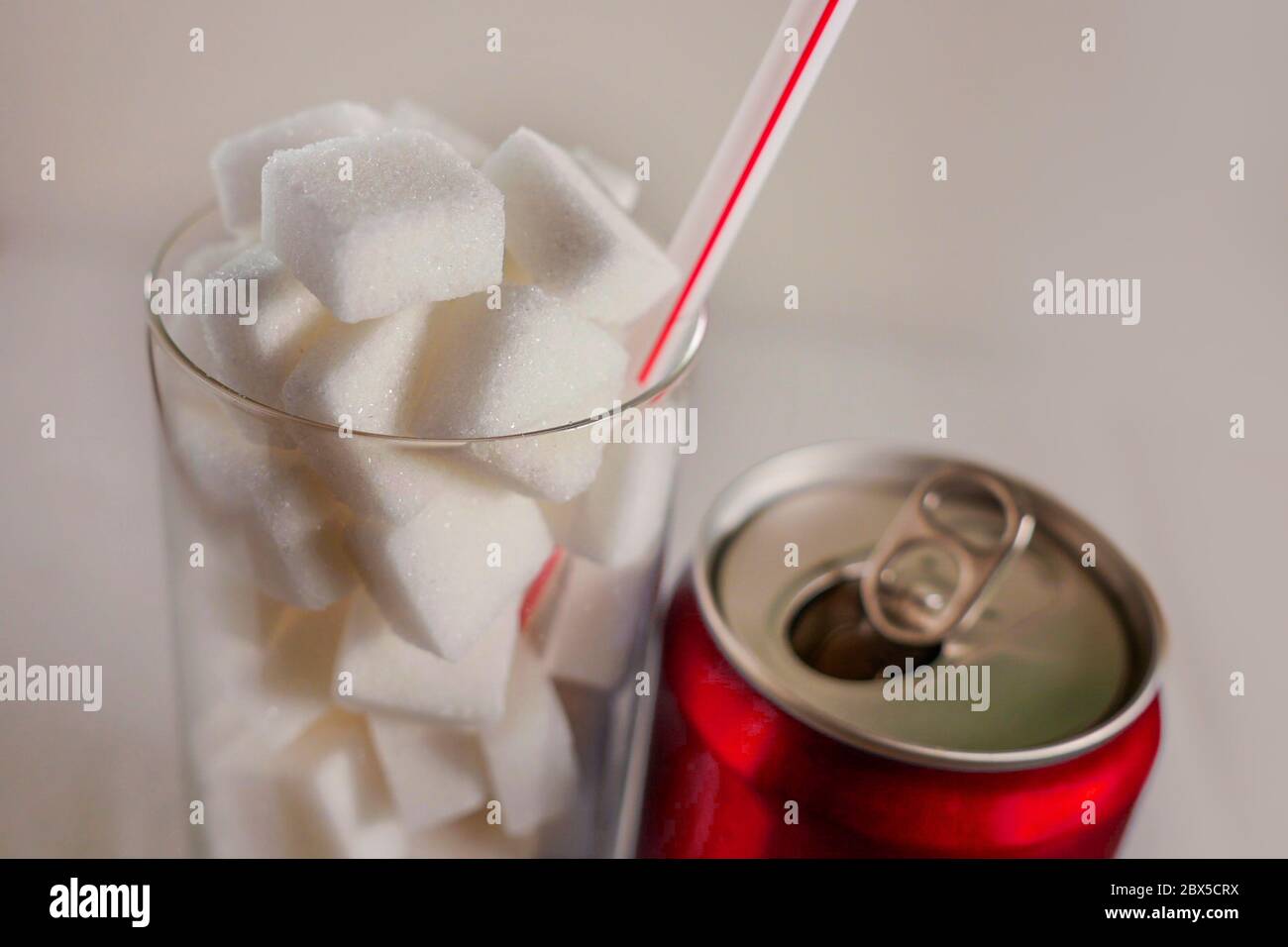 conceptual still life image of glass with straw full sugar cubes and ...