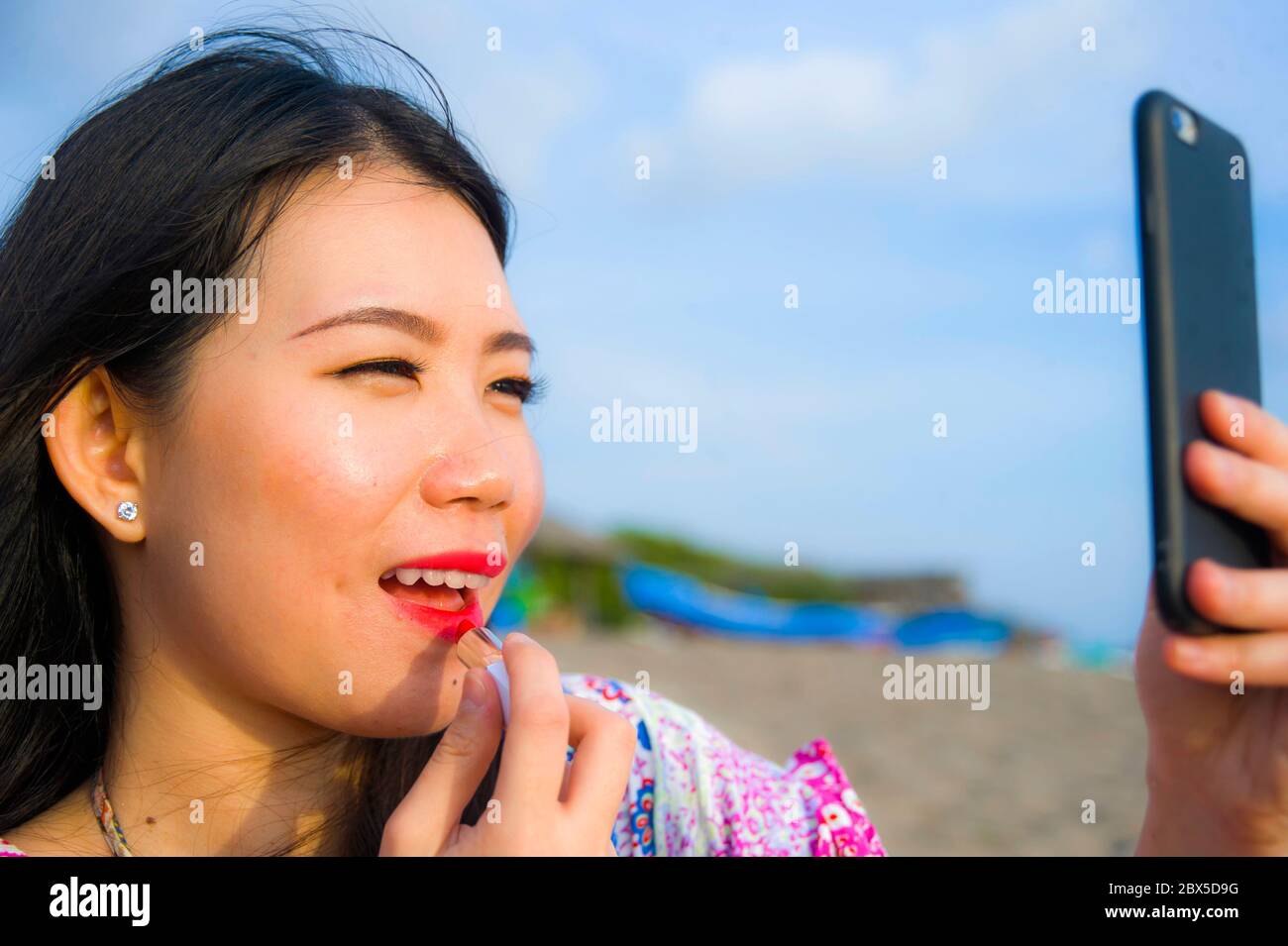 young happy and beautiful Asian Chinese woman retouching her makeup ...
