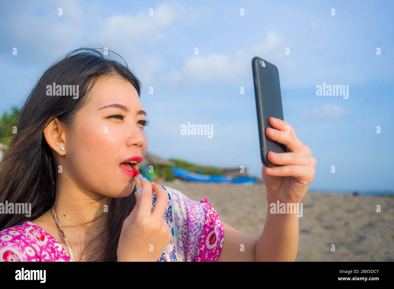 young happy and beautiful Asian Chinese woman retouching her makeup ...