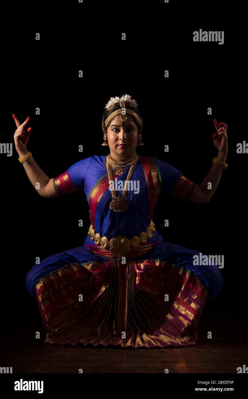 Bharatnatyam dancer in a devi pose during her performance on a dark ...