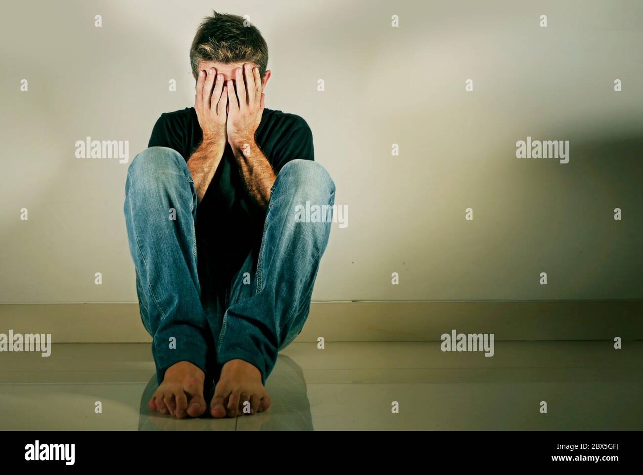 young desperate and depressed man crying alone sitting at home floor in ...