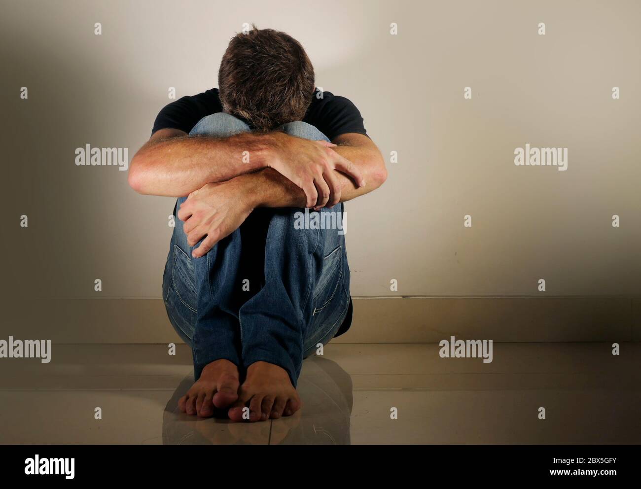 young desperate and depressed man crying alone sitting at home floor in ...