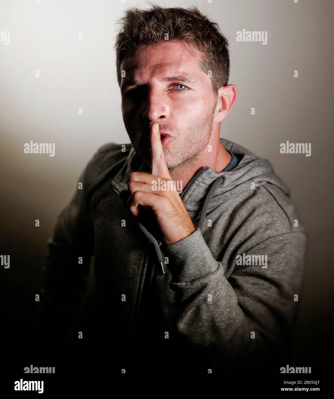 young attractive and cool man with finger on lips in silence and shut ...