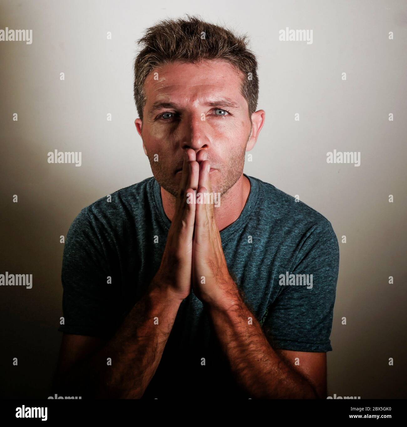 young attractive man looking anxious with hands on his mouth imploring ...