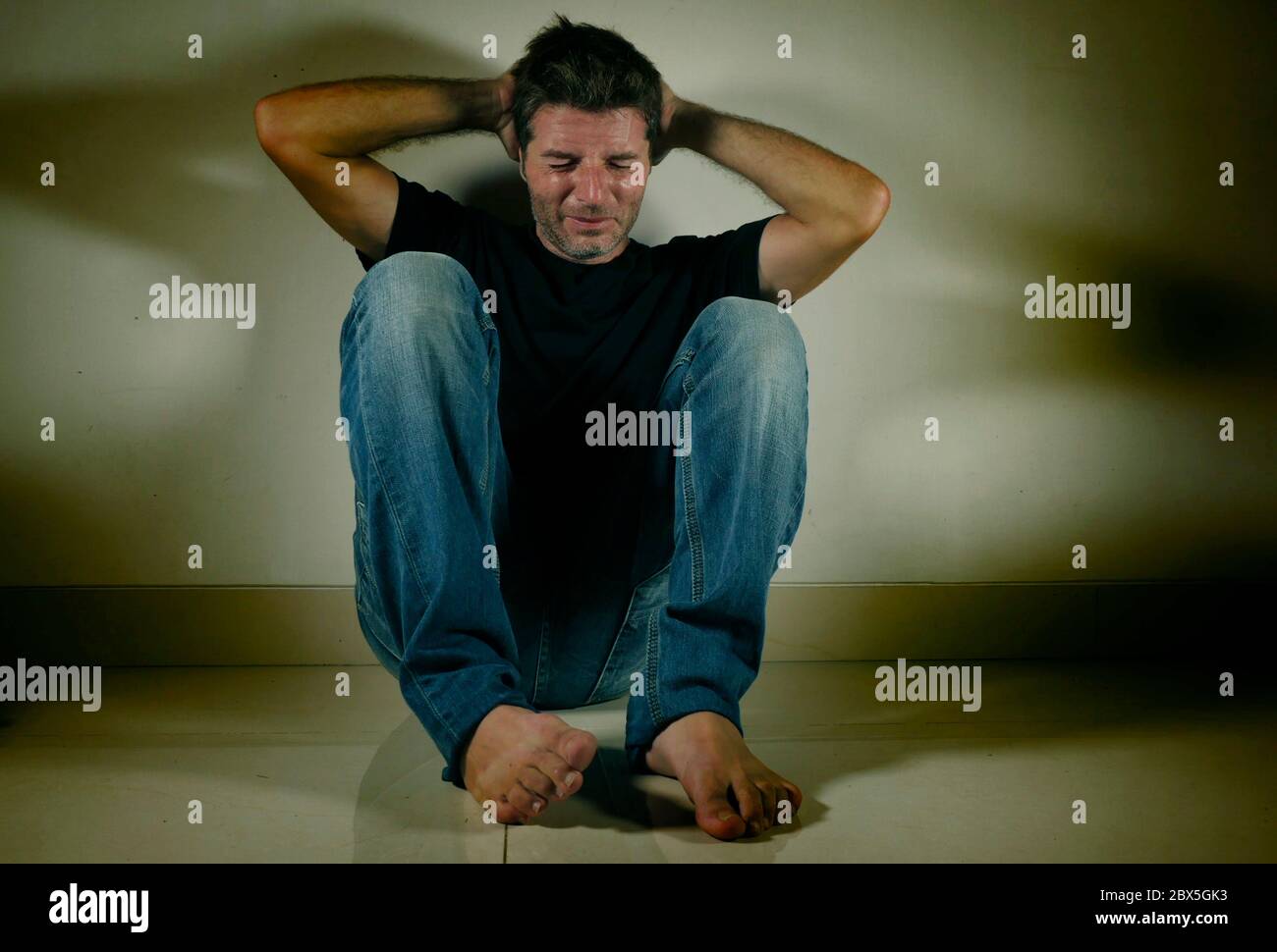 young desperate and depressed man crying alone sitting at home floor in ...