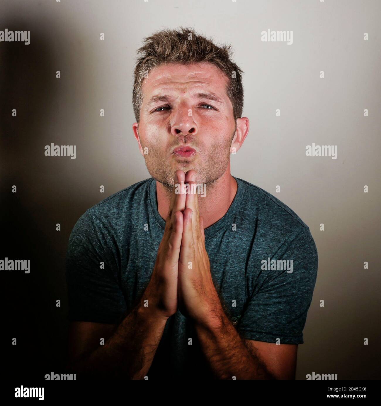 young attractive man looking anxious with hands on his mouth imploring ...