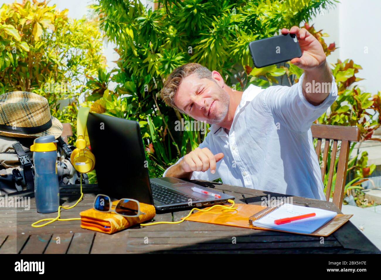young attractive and happy digital nomad man working outdoors from ...