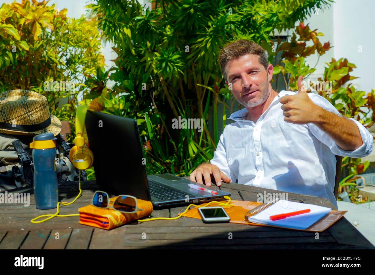 young attractive and happy digital nomad man working outdoors from ...