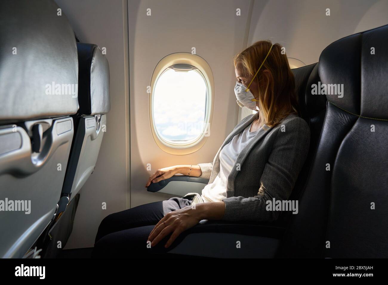 Woman wearing a face mask on a flight Stock Photo - Alamy