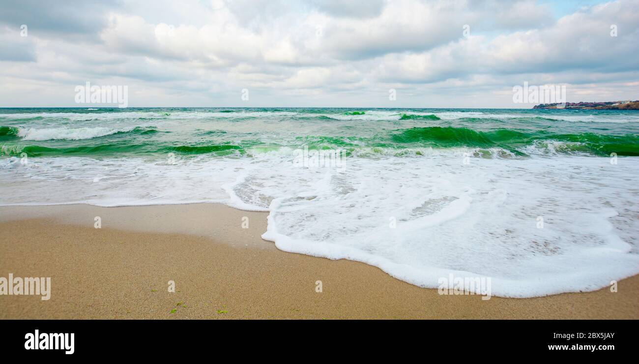 sea tide on a cloudy evening. waves crashing sandy beach Stock Photo ...