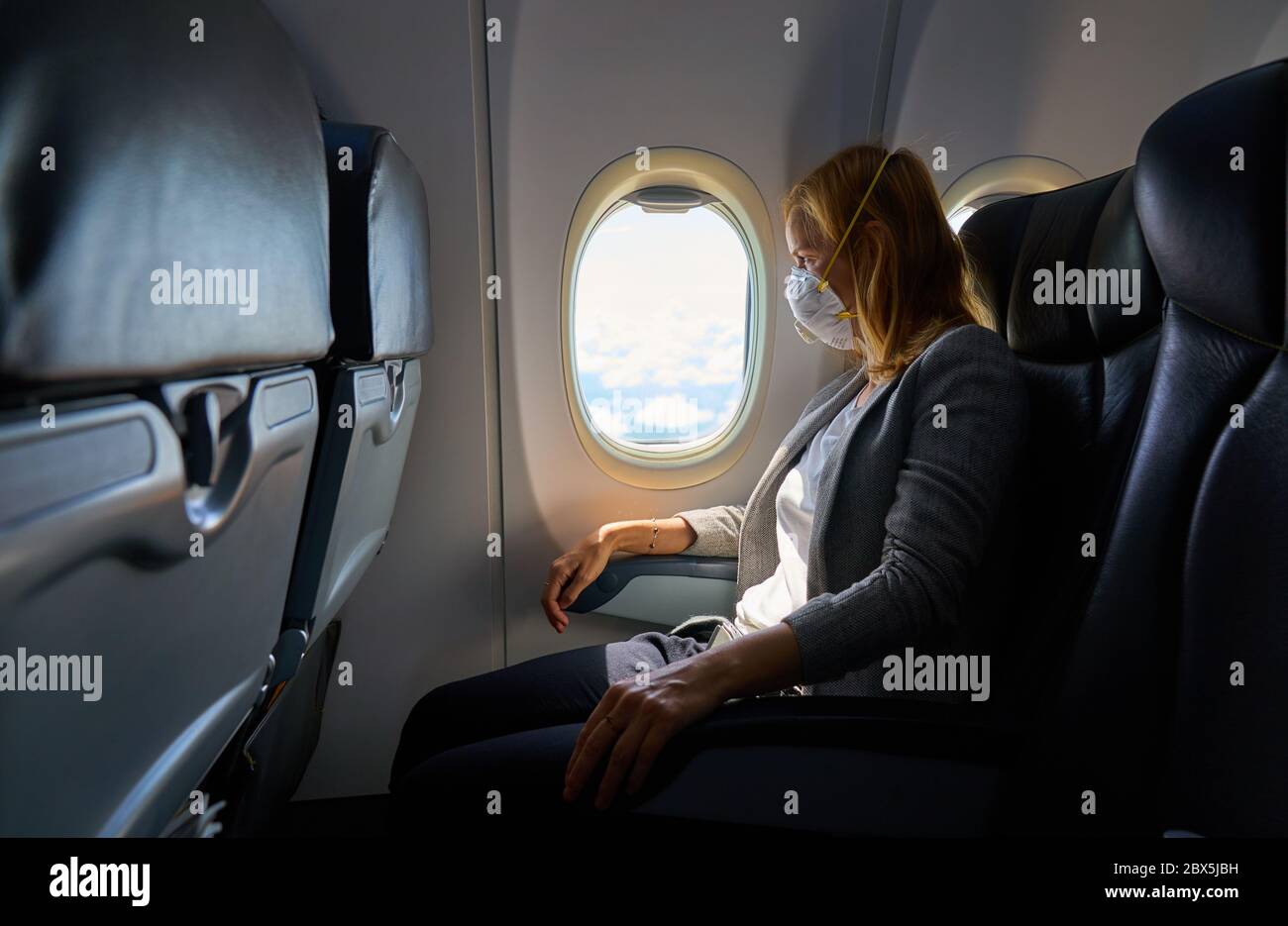 Woman wearing a face mask on a flight Stock Photo - Alamy