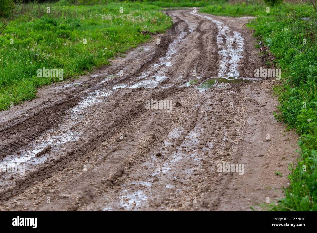 dirty clay mud road with puddles and tire tracks - closeup with ...