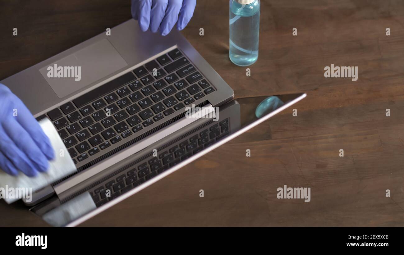 Doctor cleaning laptop computer working surface with antiseptic napkin ...
