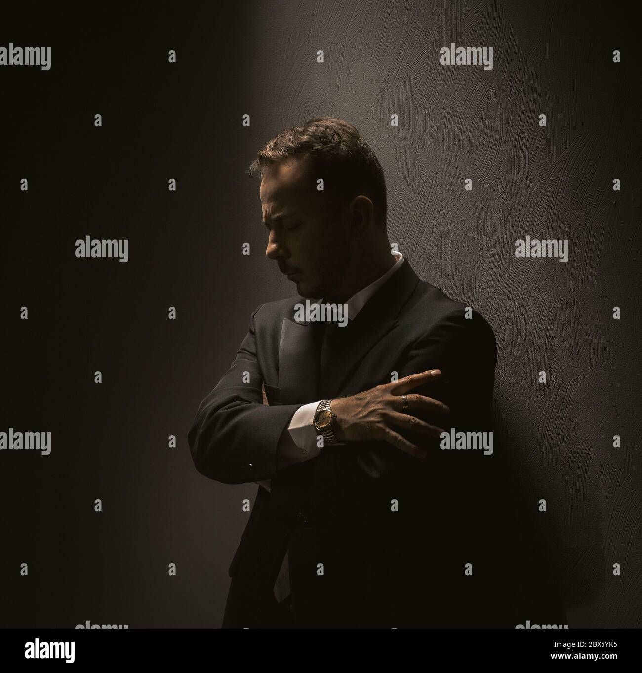 Pensive businessman stands against dark background. Thinking middle ...