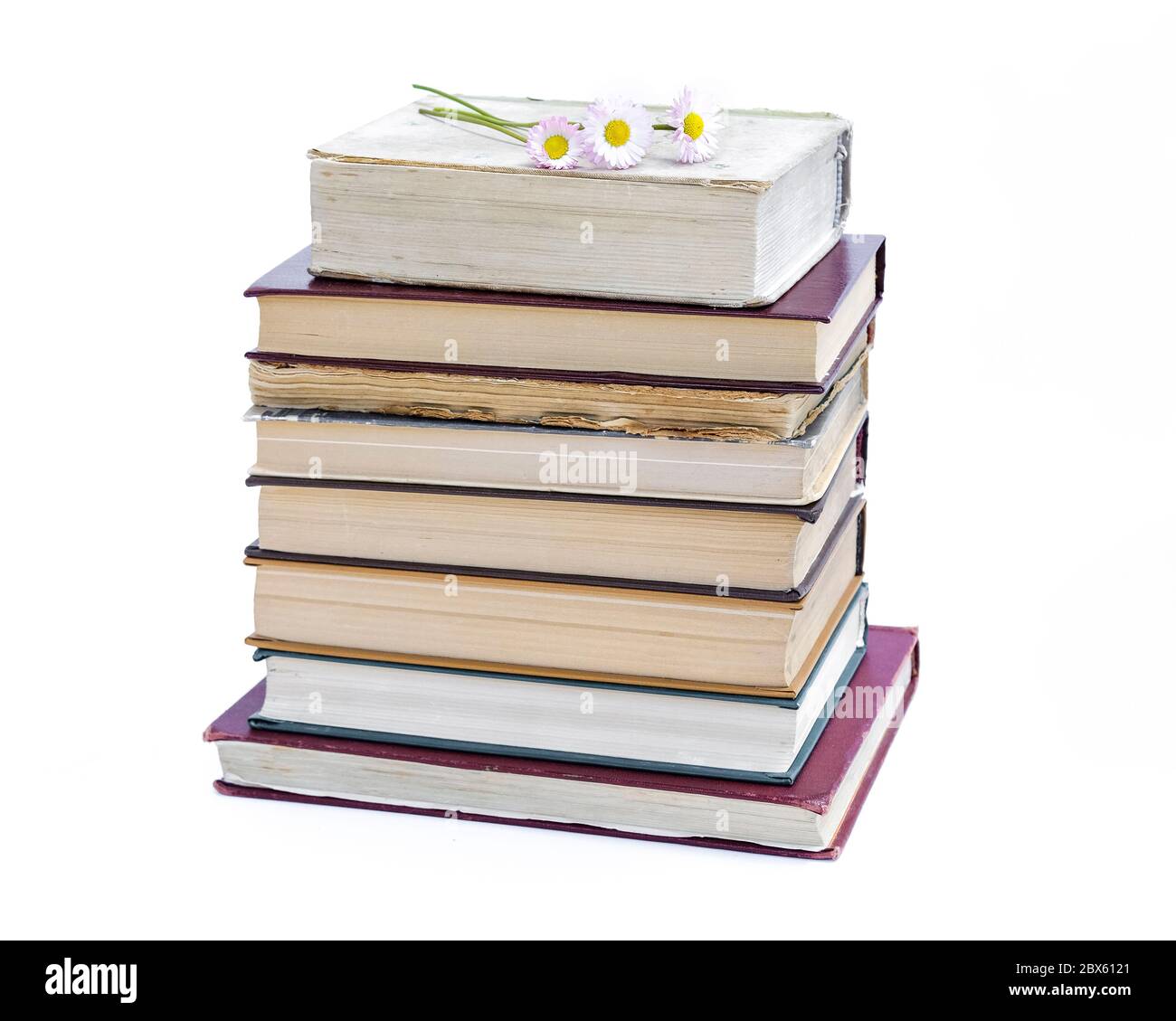 a stack of old books. bouquet of flowers from daisies on a white ...