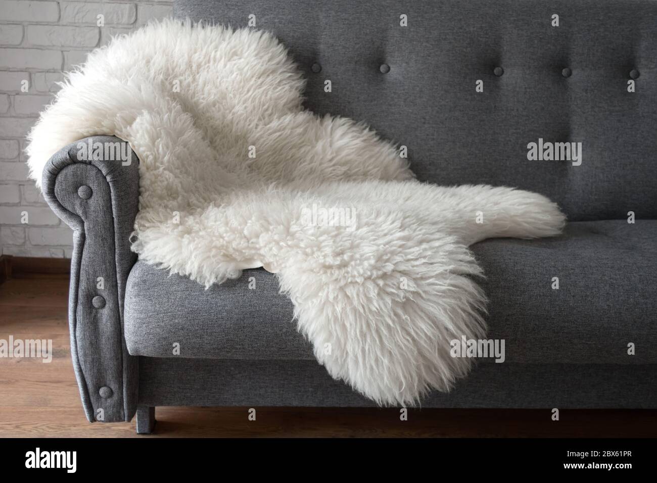 White sheep skin on a gray sofa. A cozy place to relax in the apartment ...