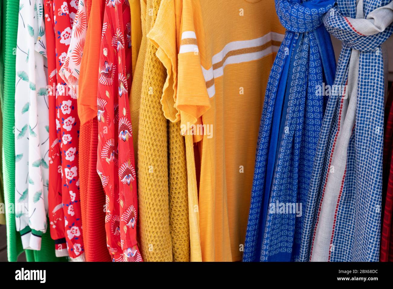 Rainbow colored clothes on hangers in a retail shop in Fashion and ...