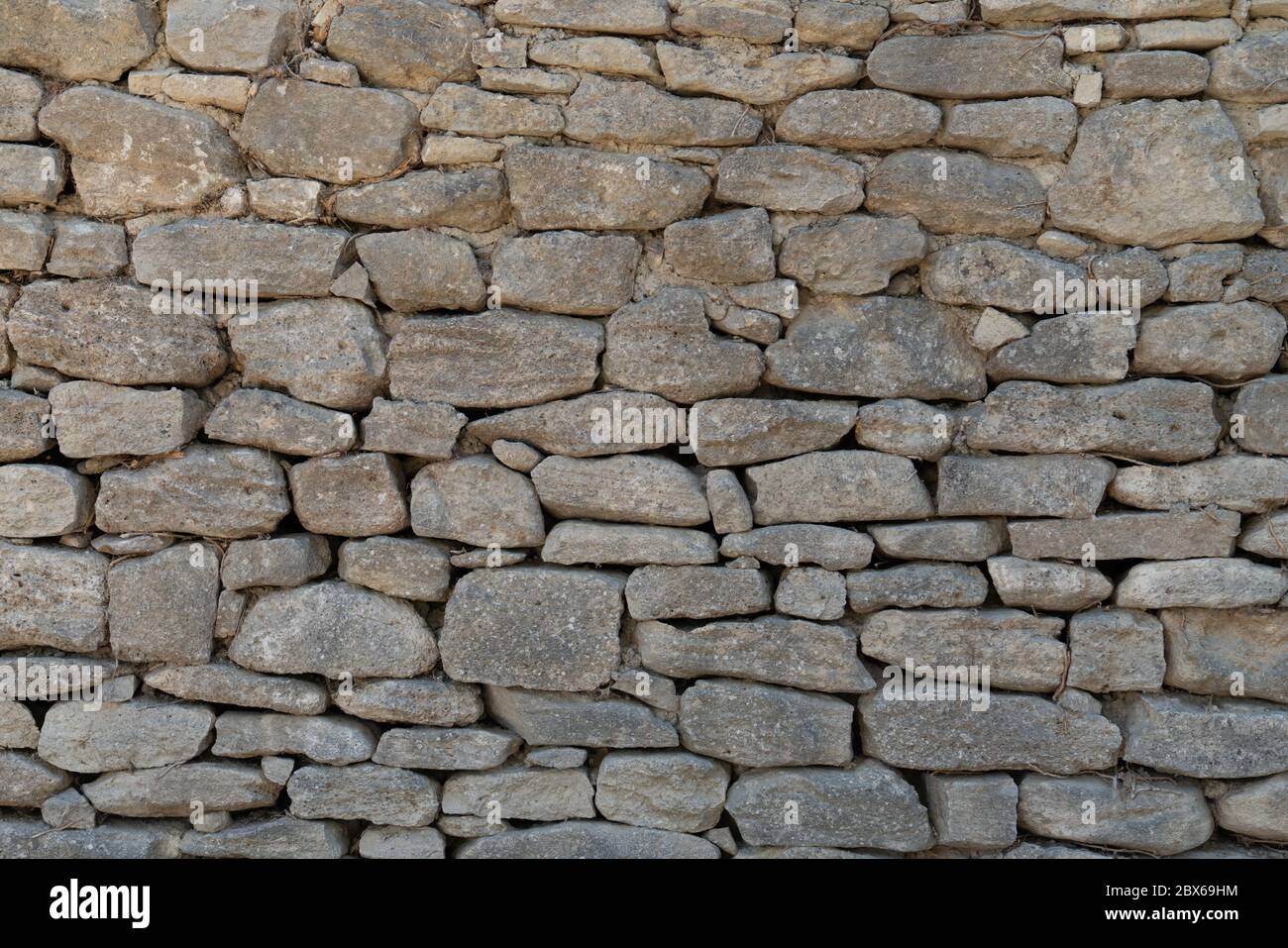 Old gray wall made of large and small rectangular hewn natural stones ...