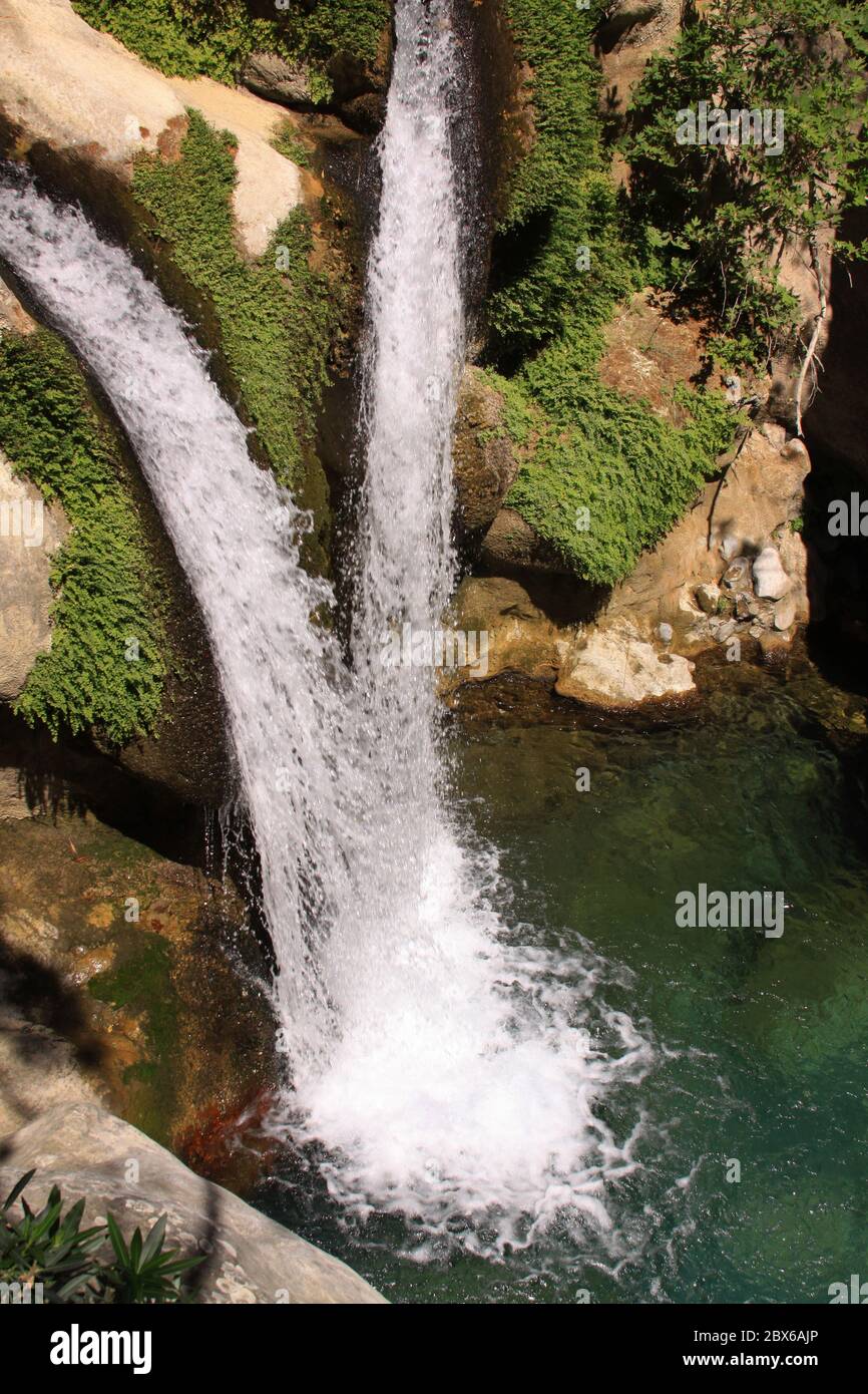 Two waterfalls meet as they flow downstream in a clean pond in natural ...