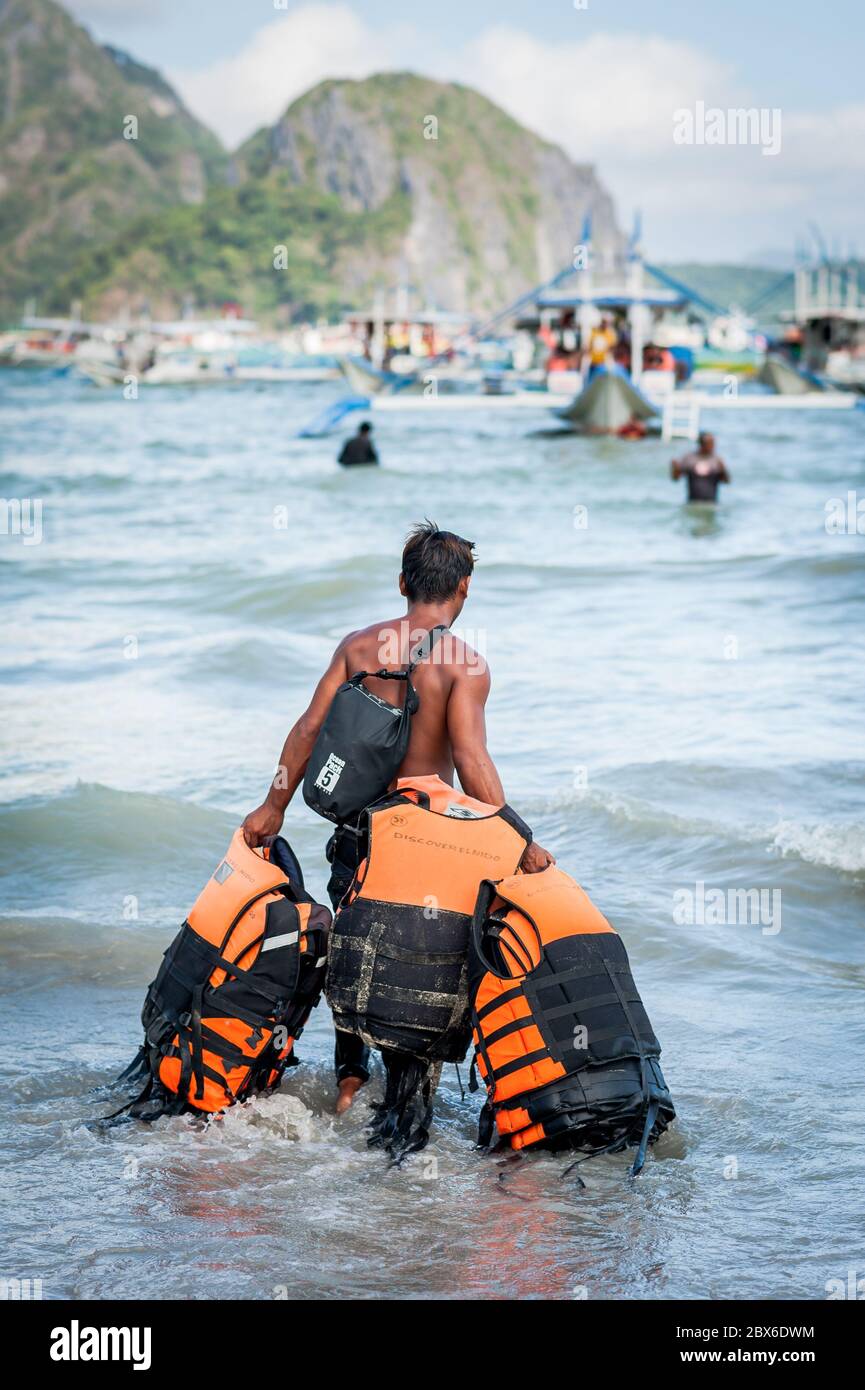 El Nido boat hands and captains wade out with supplies to the day boats ...