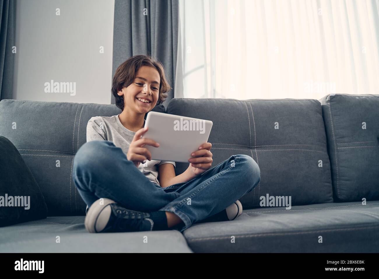 Small child sitting on the sofa and crossing legs Stock Photo - Alamy