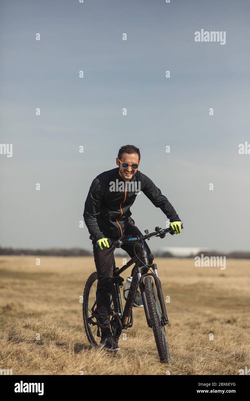 Young man riding a bike on grass field Stock Photo - Alamy