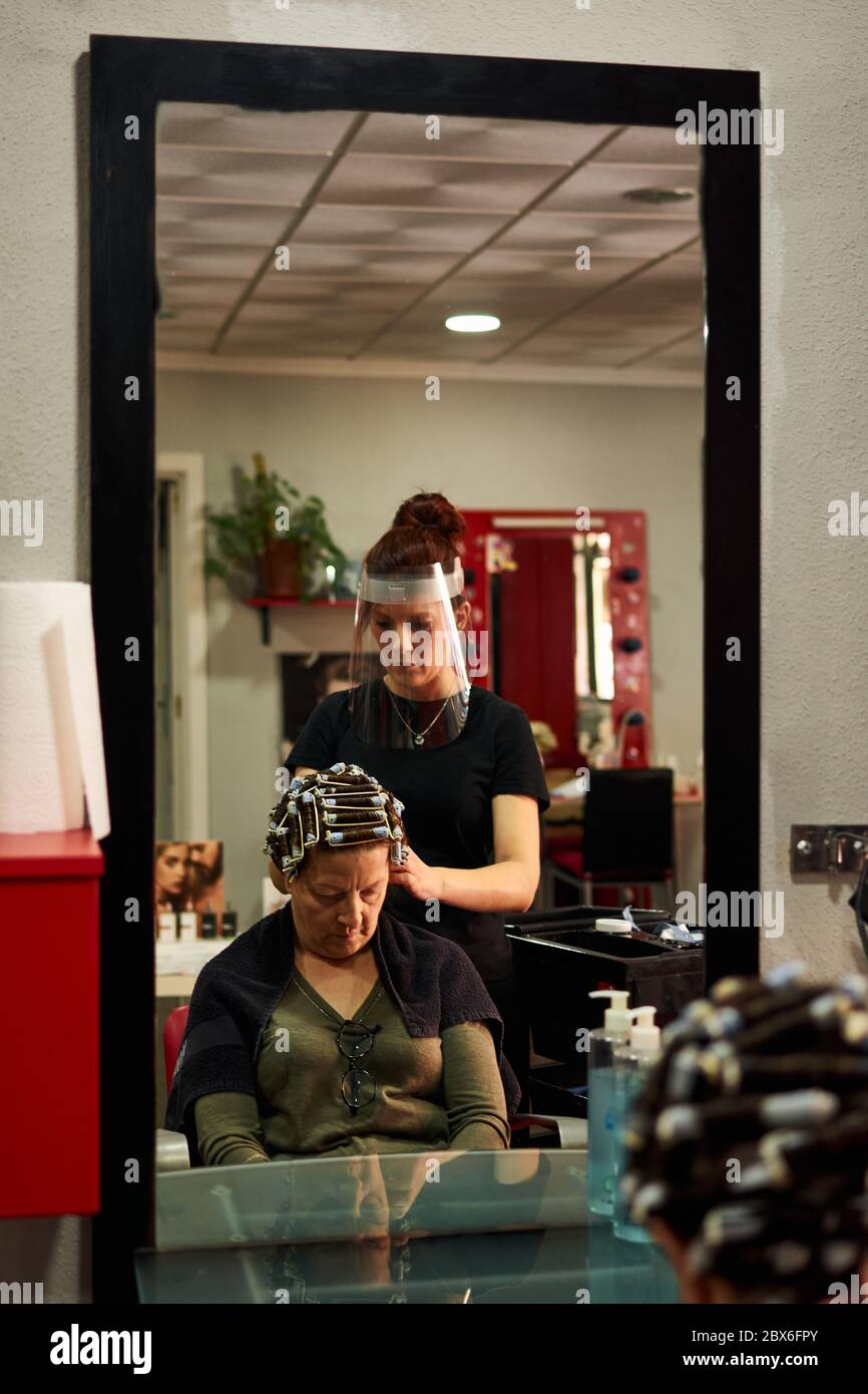 Hairdresser combs a client with a face shield in her salon Stock Photo ...