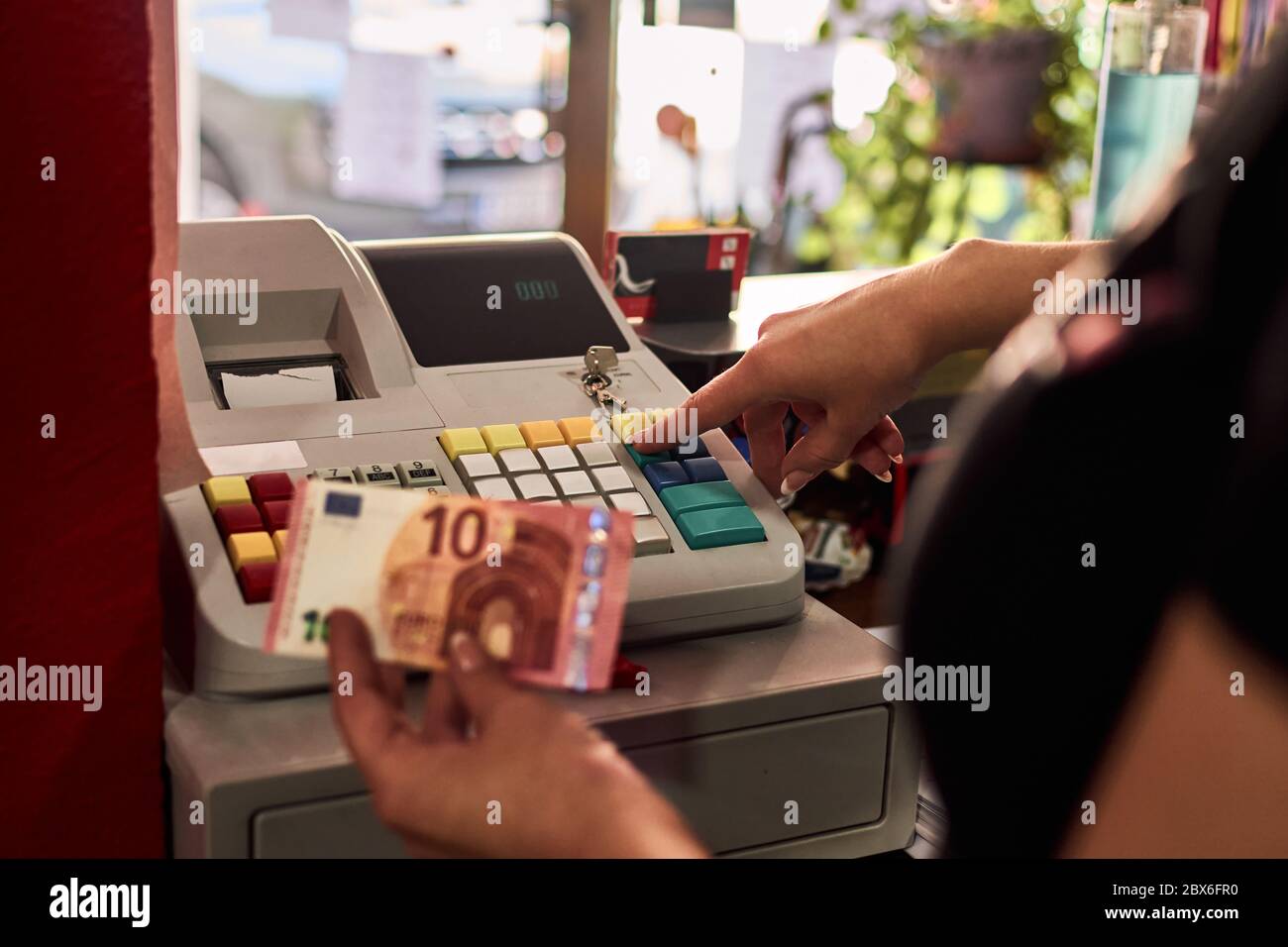 A hairdresser puts her money in her cash register. Small business Stock ...