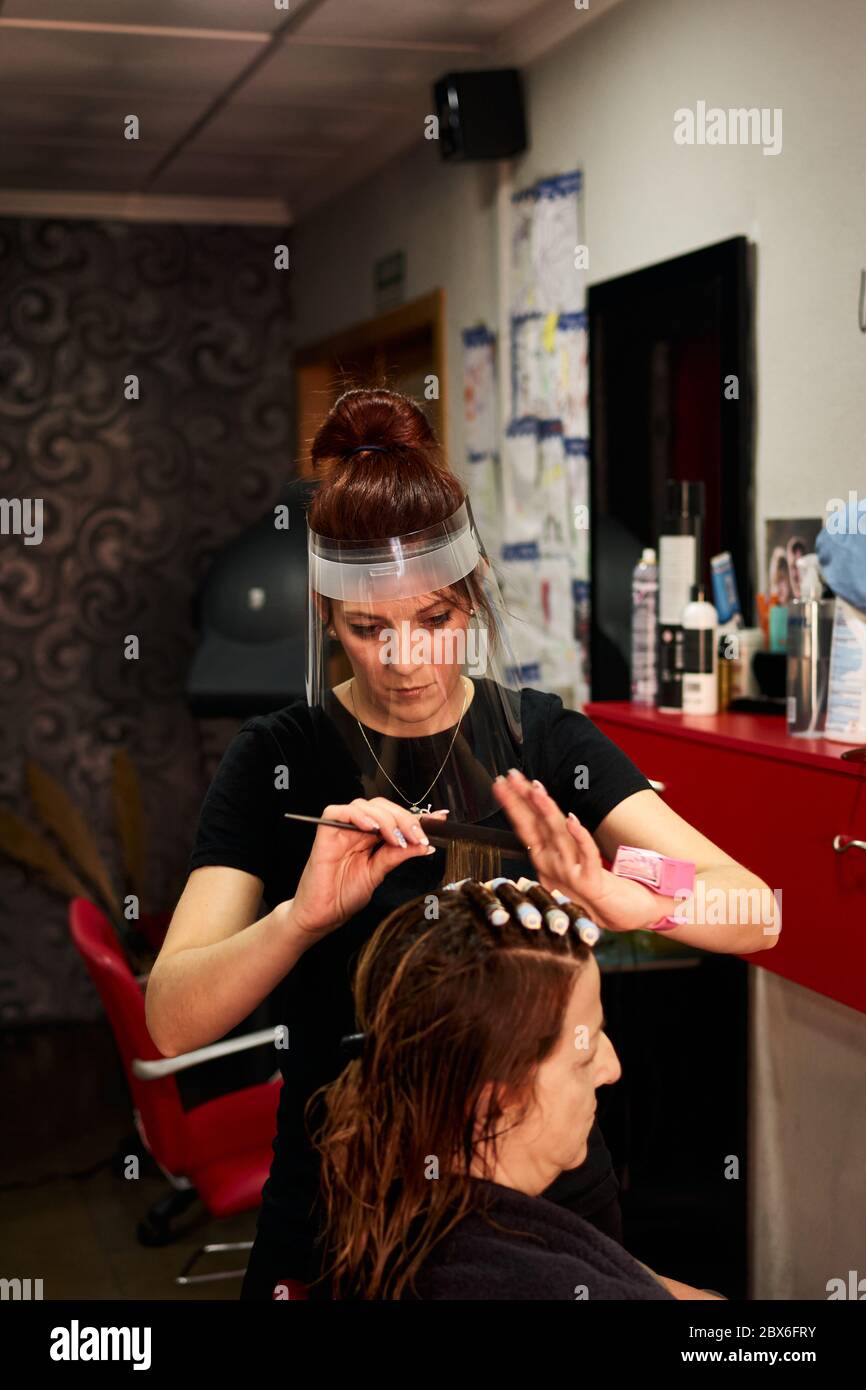 Hairdresser combs a client with a face shield in her salon Stock Photo ...