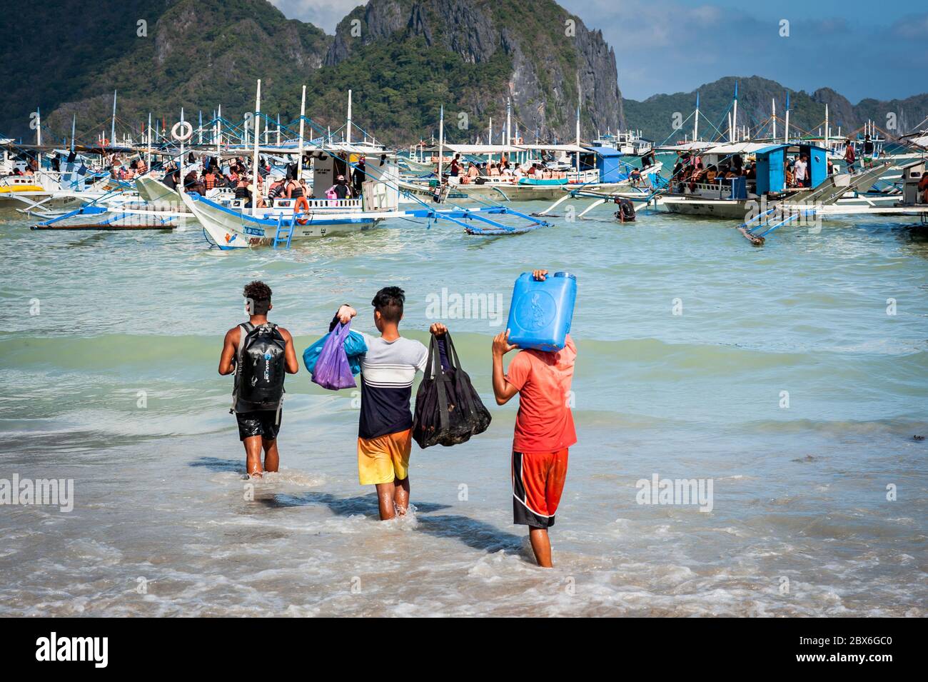 El Nido boat hands and captains wade out with supplies to the day boats ...