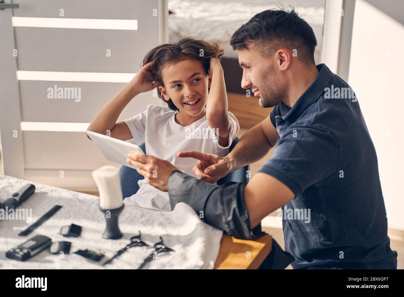Smiling handsome man explaining little child about haircut Stock Photo ...