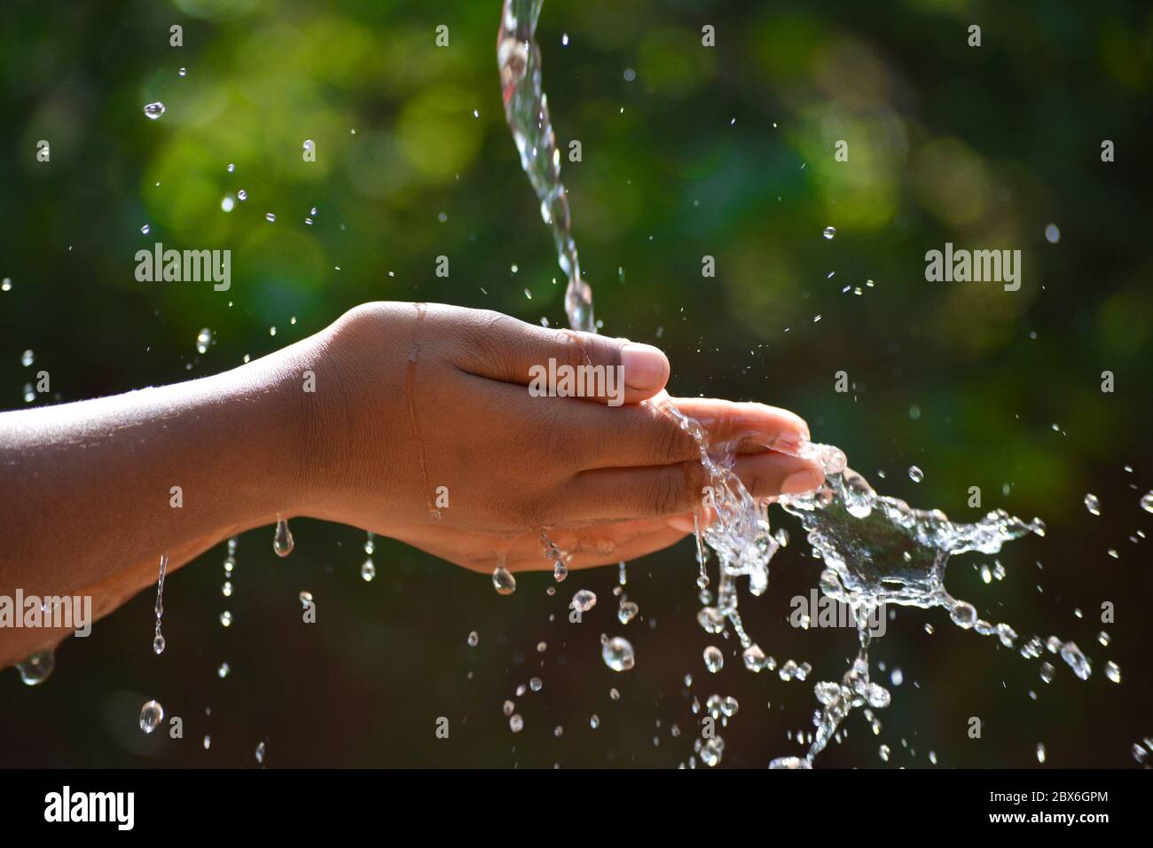 Water pouring in kid two hand on nature background. Hands with water ...