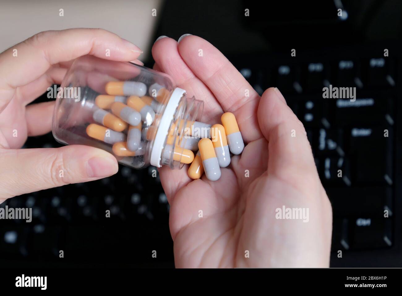 Bottle of pills in female hands on PC keyboard background. Woman with ...