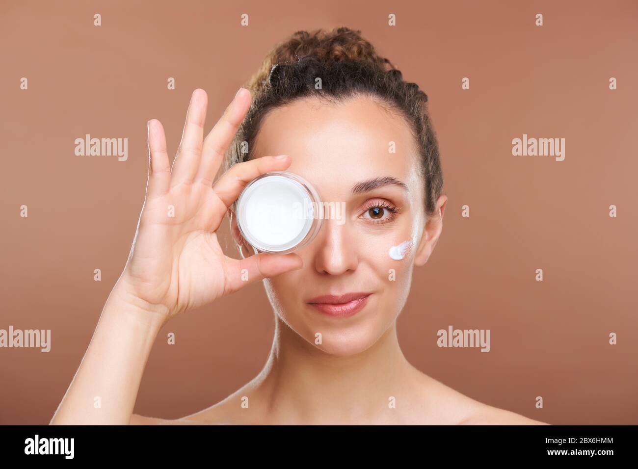 Healthy young beautiful woman holding small jar of rejuvenating facial ...