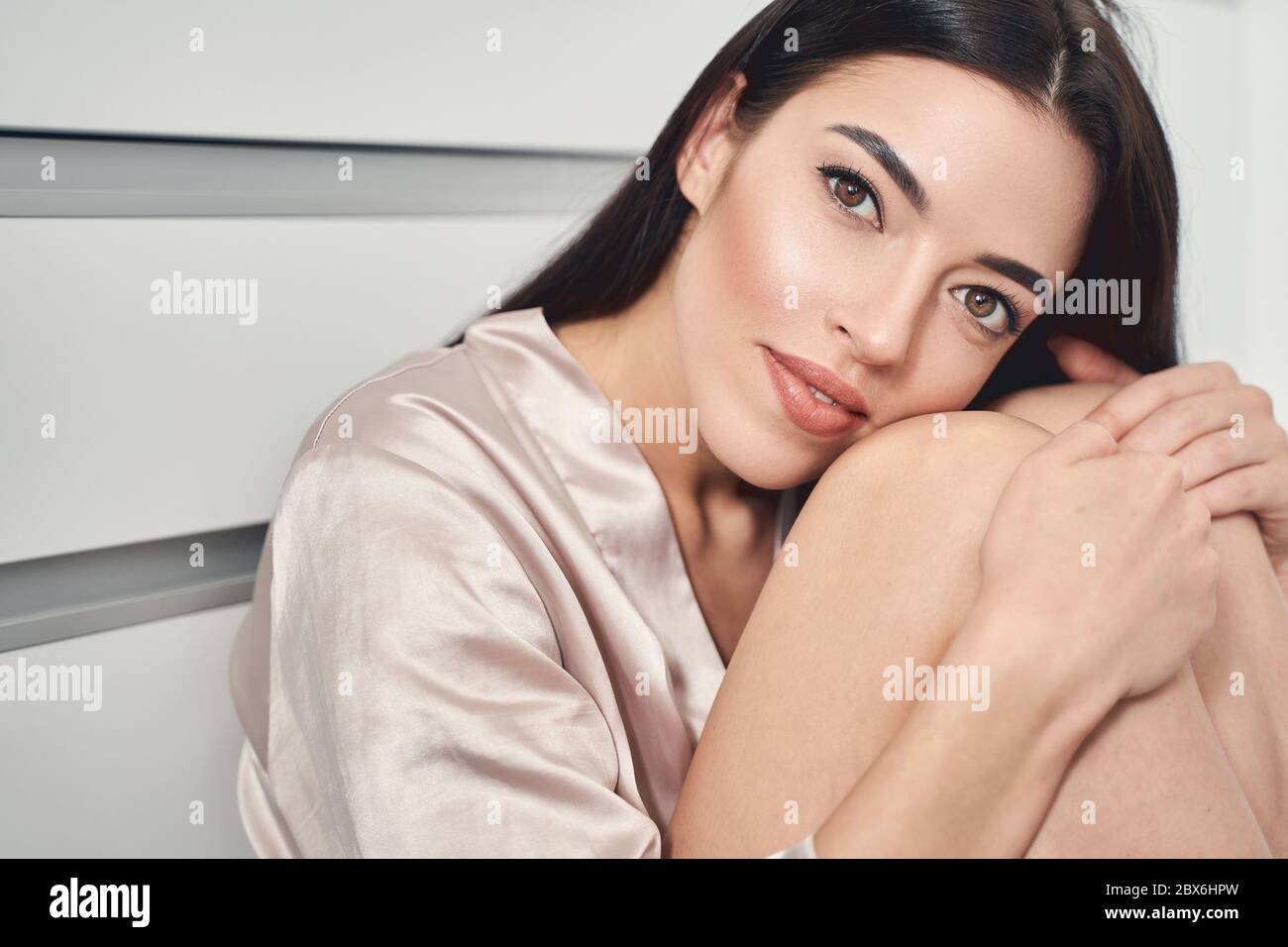 Pretty young lady embracing her knees with smile Stock Photo - Alamy