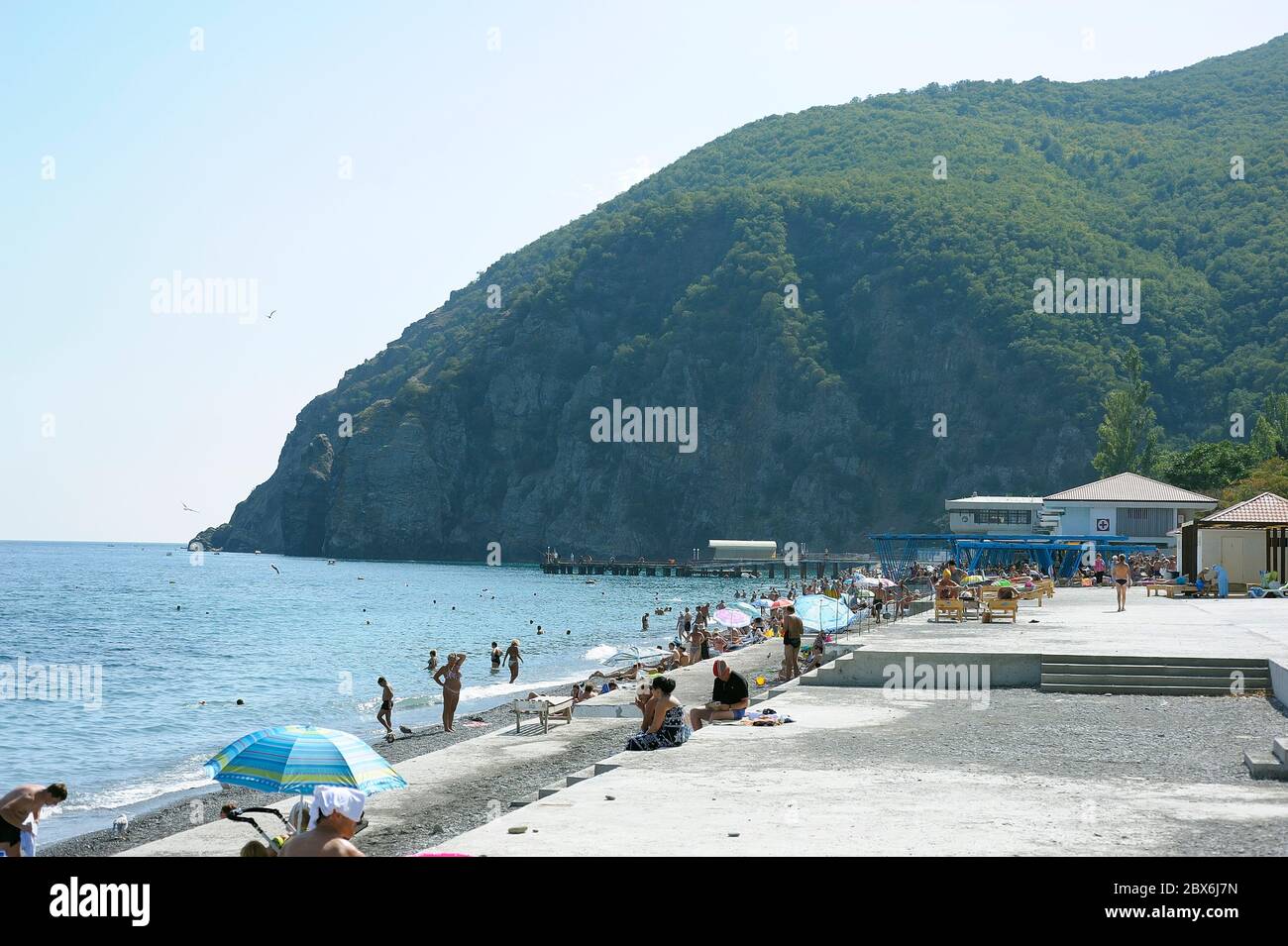 View of the stony beach of Alushta town, beachgoers sunbathing and ...